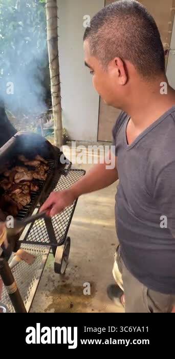 man putting meat on grill grate to cook meat in traditional way over ...