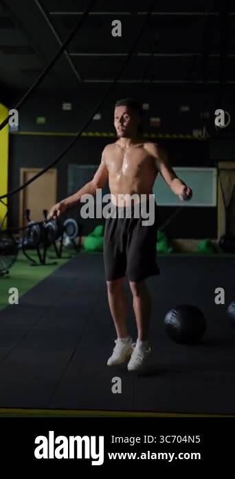 A fit individual performs jump rope exercises in a modern gym ...
