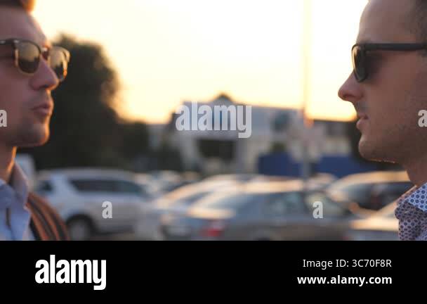 Two young business men standing outdoor near parking and talking ...