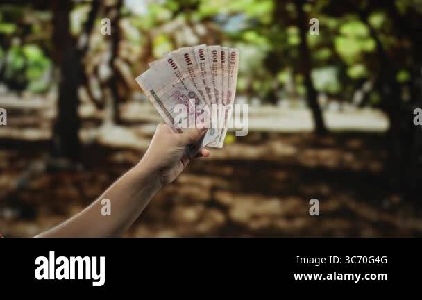 Man holding saudi riyal banknotes in hand outdoors in a park ...