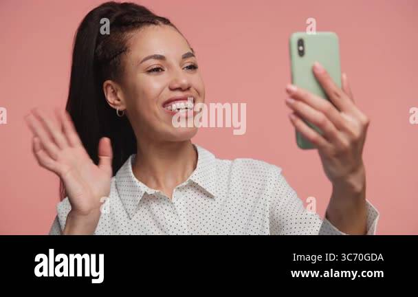 Cheerful young woman using a smartphone for a video call, smiling and ...