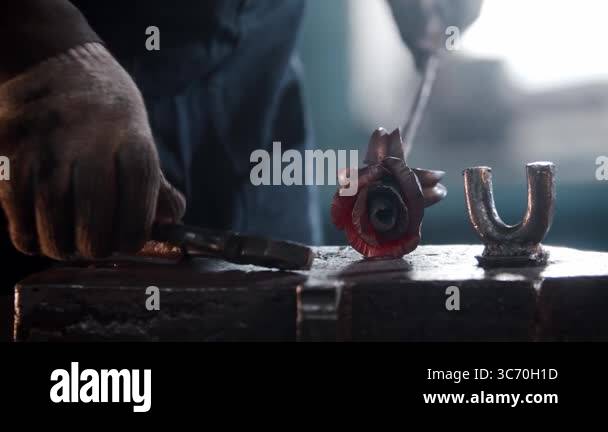 Metalworker bending glowing hot metal rod into shape of a rose Stock ...