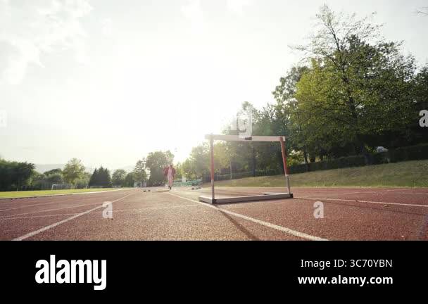 Businessman jumping a hurdle while running on the athletics racing ...