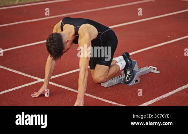 Strong Young Man Starting a Race From Track Starting Blocks Position on ...