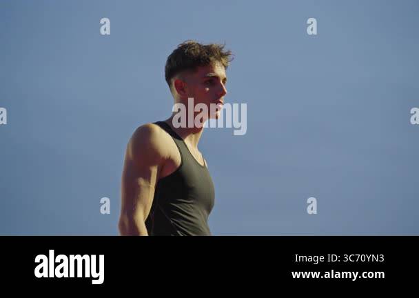 A man is resting after hard exercise on an athletics race track. He ...