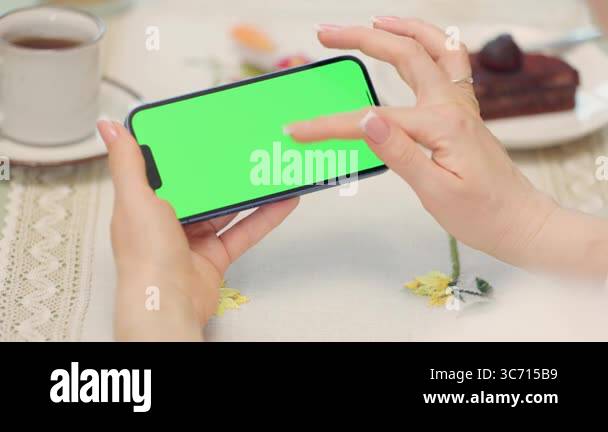 Close-up Of Mobile Phone With Green Mock-up Screen In Female Hands. Woman Uses Smartphone While ...