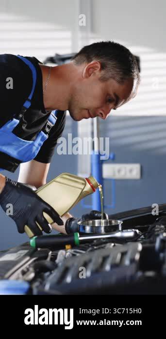 Vertical Format Video of The mechanic is pouring oil into the engine ...