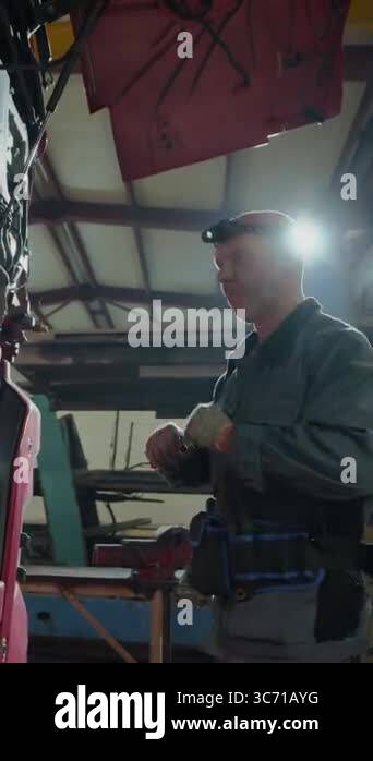 Vertical handheld shot of skilled middle-aged Caucasian male mechanic ...