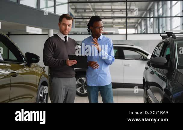 A car salesman and an African American customer discuss vehicle options ...