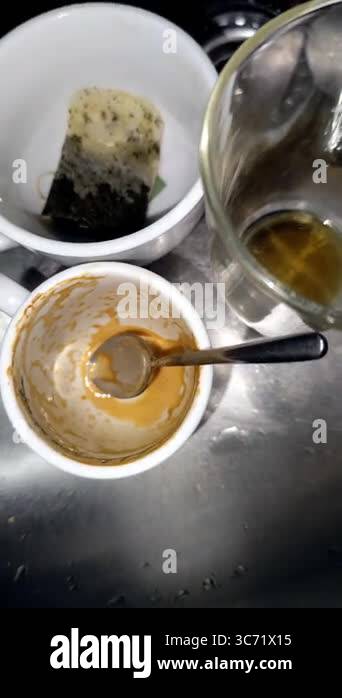 Leftover coffee and tea in dirty cups with tea bag and spoon in metal ...