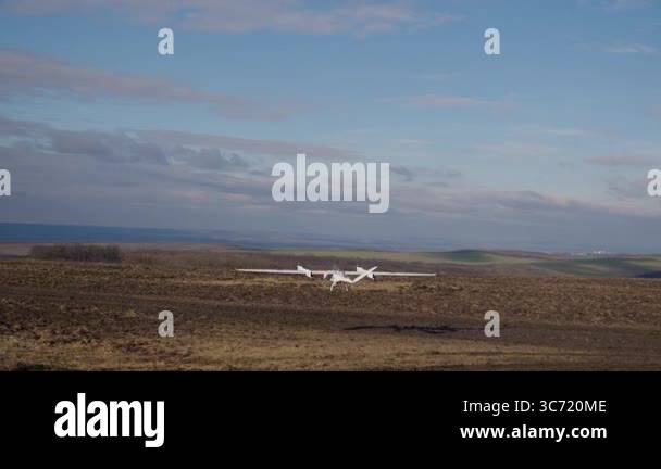 White drone takes off from the ground at high altitude over open fields ...