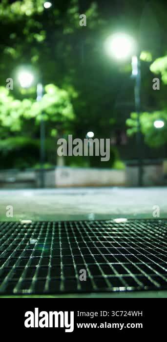 Storm sewer. Light rainfall. Puddle with lights reflection on city ...