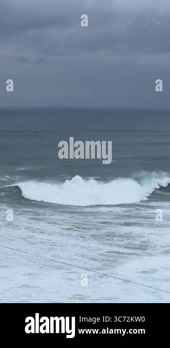 Powerful ocean waves crash against the cliffs of Nazare, Portugal ...