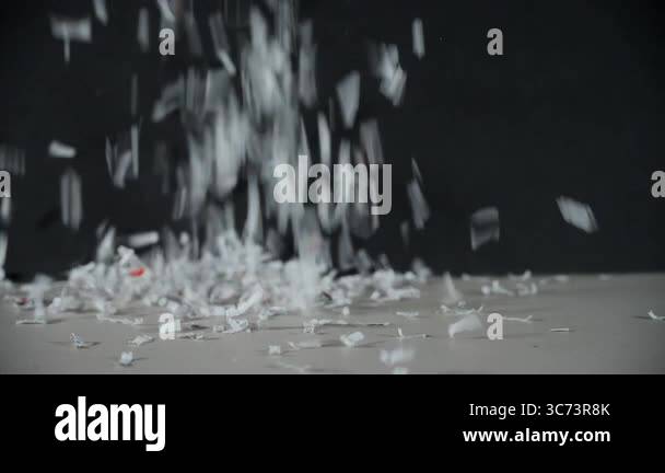 Shredded office paper falling onto a table, creating a pile. Slow ...