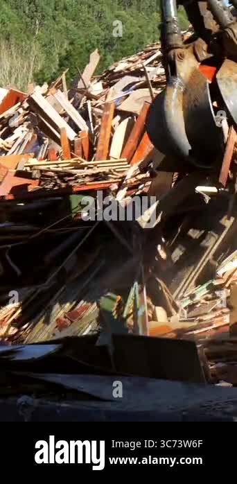 Excavator claw efficiently sorting and moving wood waste at a recycling ...