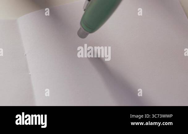 Close up of blank paper notepad with green pen tapping waiting for ...