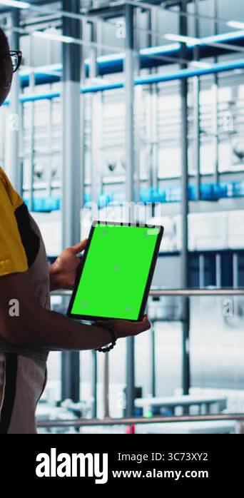 Vertical video Smart factory engineer implements automated workflows using green screen tablet ...