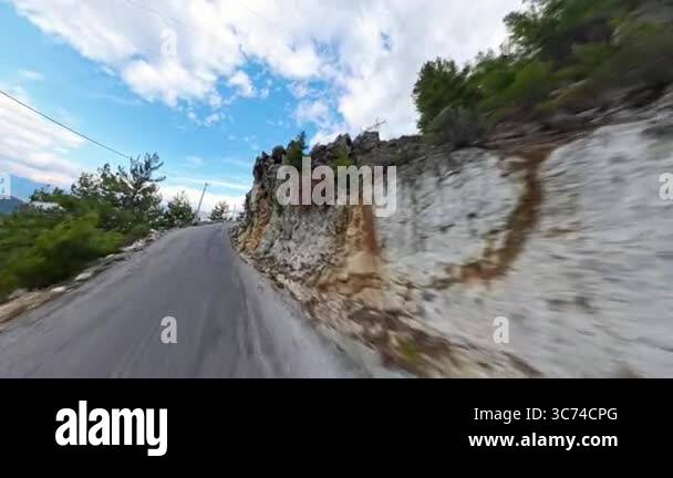 Winding dirt road with sharp curves flanked by rocky slopes and sparse ...
