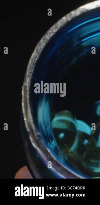 Vertical video. A Hand Throwing a Golden Transparent Omega 3 Capsule ...