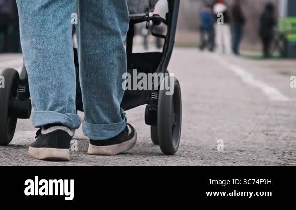 Low-section shot of a womans legs as she pushes a baby stroller on a ...