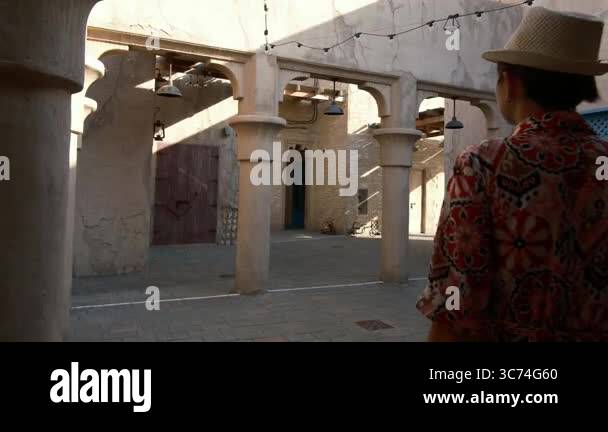Young woman in ethnic dress and hat exploring Al Seef Park in Dubai ...