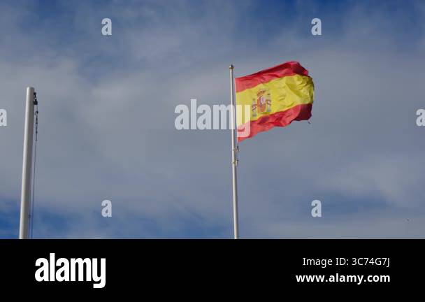 Spanish flag waving gracefully against a bright blue sky. A powerful ...