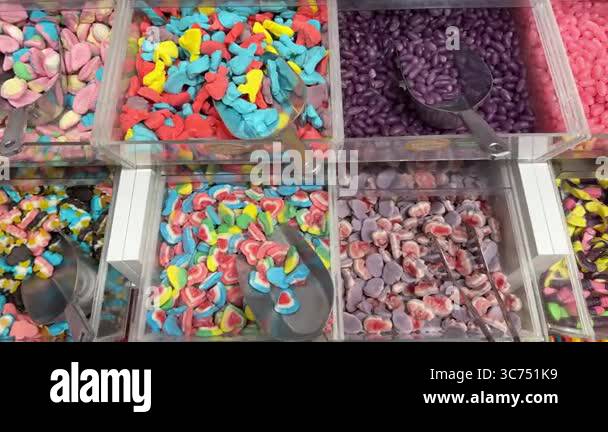 Colorful candy assortment displayed in clear bins at a candy store with ...