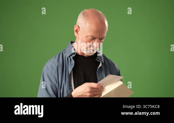 A mature man with a happy, positive, thoughtful expression is reading a ...