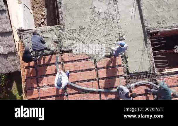 Masons placing cement on the roof of a house. Men working in ...