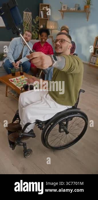 Vertical high angle shot of young Caucasian man in wheelchair holding ...