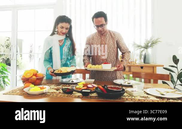 Indian couple in traditional attire setting table for family dinner at ...