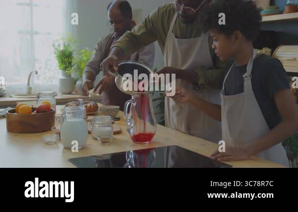 African American father and little son straining Zobo tea into glass ...