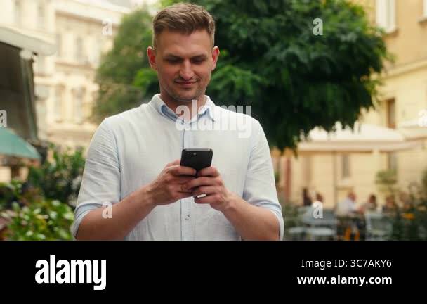 Smiling Caucasian man outside texting message typing sms using ...