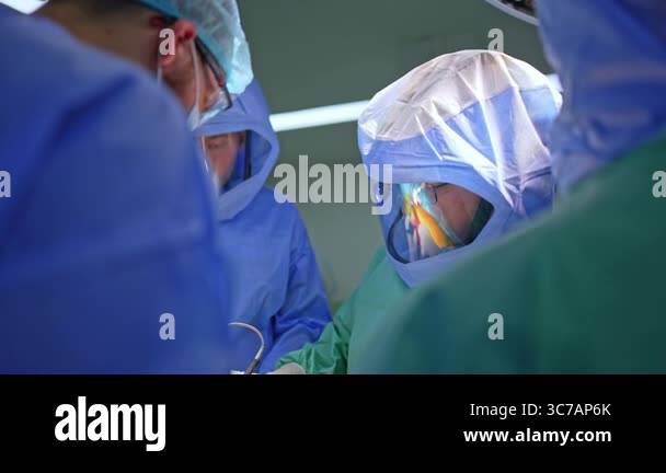 Uniformed male medics cooperating at surgery. Surgeons wear protective ...