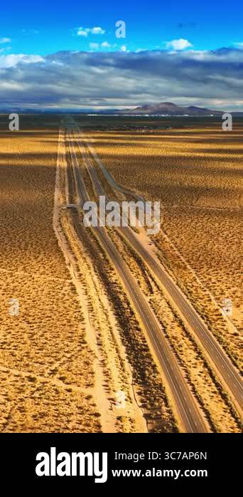 View of a desert in California covered with little bushes. Highway lies ...