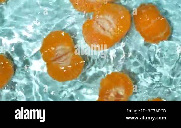 Peeled fresh mandarin halves in water, splash water, top view, slow ...