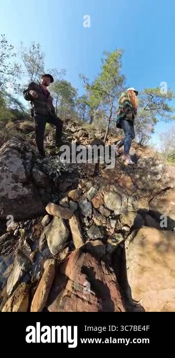 Vertical video. Wide-Angle View of Two Hikers Climbing Over Rocky ...