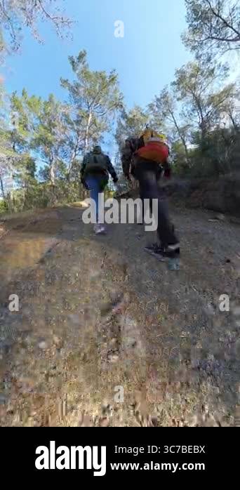 Vertical video. Two Hikers Walking Uphill on a Rocky Trail in a Dense ...