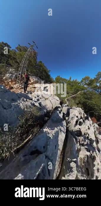 Vertical video. Man Climbing Over Large Rocks on a High Mountain with a ...