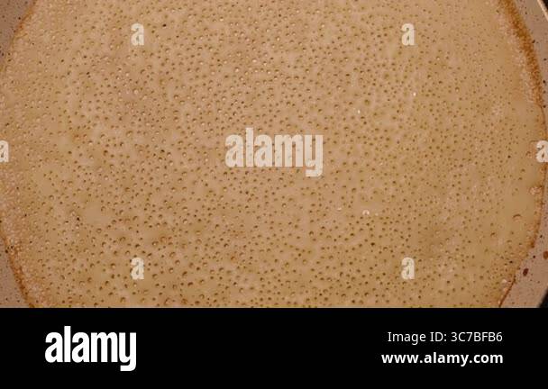Close-up of a Pancake Cooking in a Pan with Small Air Bubbles Forming ...