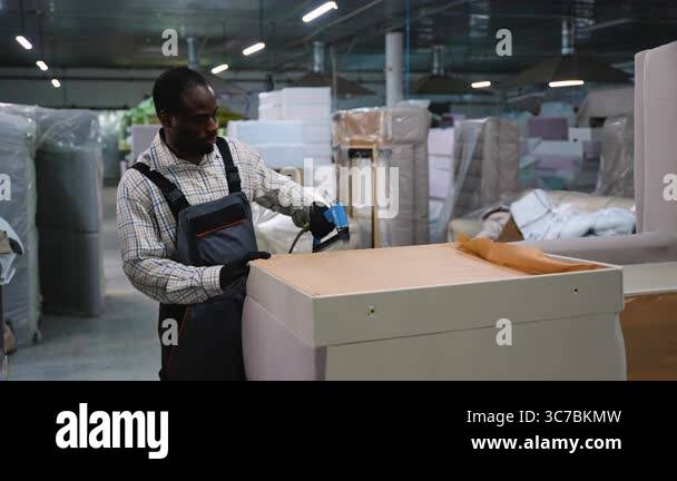 Furniture workshop worker uses electric stapler to attach upholstery ...