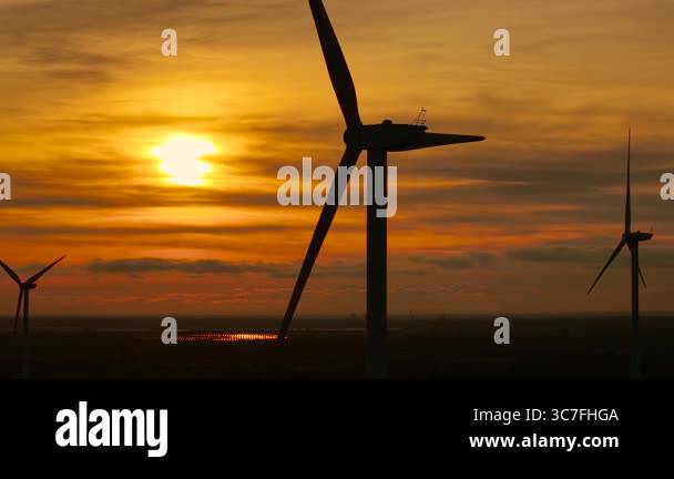 Wind farm rotating massive blades, supporting renewable power at sunset ...