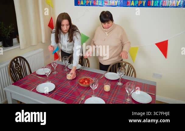 Preparing birthday table with women arranging dishes and decorations ...