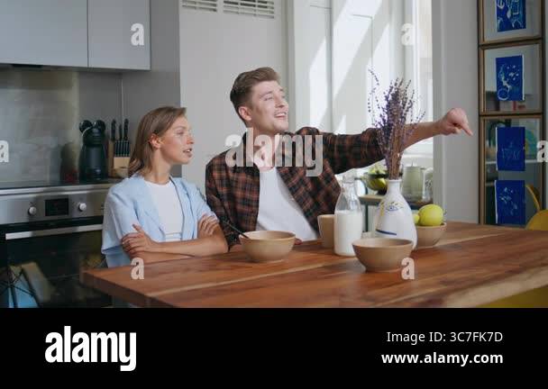 Spouses have fun together in morning kitchen. Loving man joking fooling ...