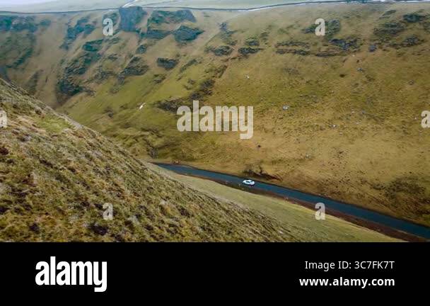 Car traveling on mountain road with steep grassy slopes. Vehicle ...