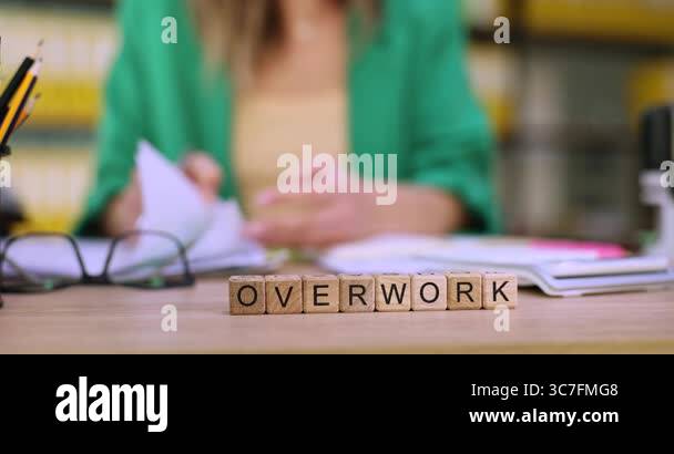 Businesswoman sits at desk and reviews stack of office papers ...