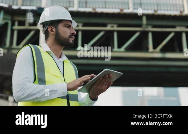 Portrait of thoughtful architect designer working on tablet computer standing near bridge ...