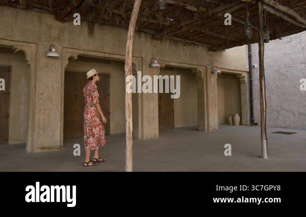 Young woman in ethnic dress and hat exploring Al Seef Park in Dubai ...