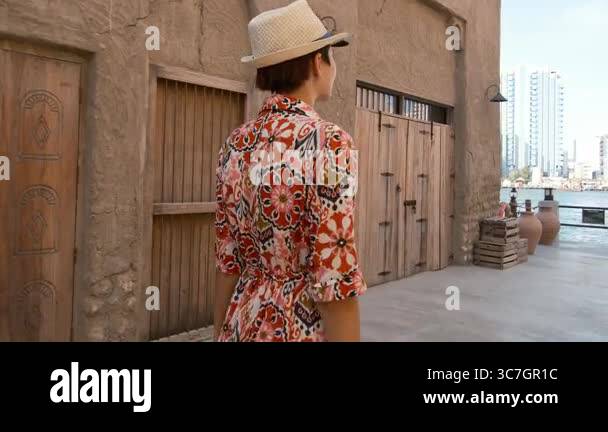 Young woman in ethnic dress and hat exploring Al Seef Park in Dubai ...