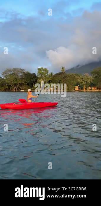 Vertical video of a happy mature woman enjoys a sunset kayak ride on ...